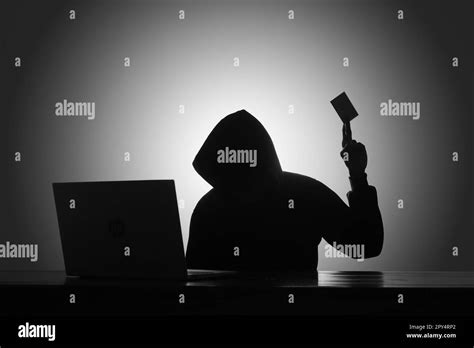 Mysterious Man Wearing Black Hoodie Using Laptop And Holding Credit