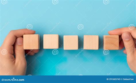 Hand Arranging Wooden Cubes On A Pastel Simple Background Providing A