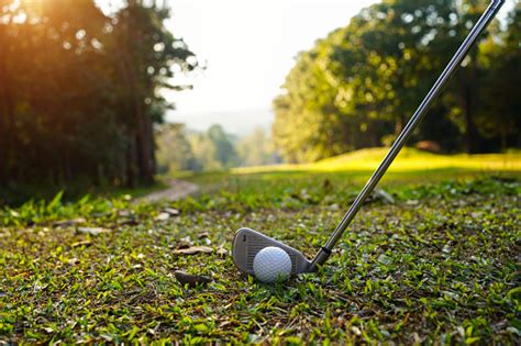 아침 햇살이 내리쬐는 아름다운 골프 코스의 녹색 잔디밭에 골프 클럽과 골프 공 골프 코스 배경에 칠 준비가 녹색 잔디에 골프 공
