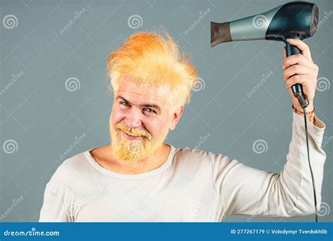 Handsome Redhead Man With Long Hair Dries His Hair With A Hairdryer