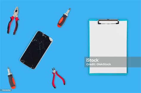검은 빈 흰 종이와 서비스에 파란색 테이블에 다른 도구와 플라스틱 클립 보드 근처 깨진 화면과 본체와 스마트 폰을 추락 했다 평면도 수리 개념입니다 복사 공간 가지치기