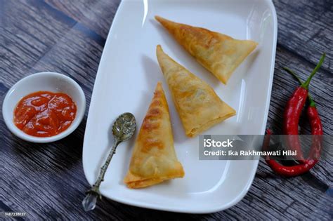 정사각형 흰색 세라믹 접시에 세 개의 사모사 사모사 Samosa Samsa 또는 Somsa는 삼각형 튀김 생과자입니다 속은 완두콩 양파 고수 잎 때로는 파니르를 섞은 매운