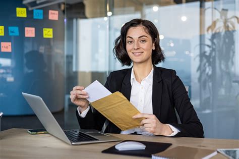 노트북이 있는 책상에 앉아 봉투를 들고 사무실에서 자신감 넘치는 사업가가 직업적 성공과 커뮤니케이션을 보여줍니다 개발에 대한 스톡 사진 및 기타 이미지 Istock