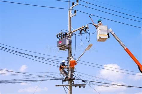Electricians Group With Crane Truck Are Installing Electrical Equipment On Electric Power Pole