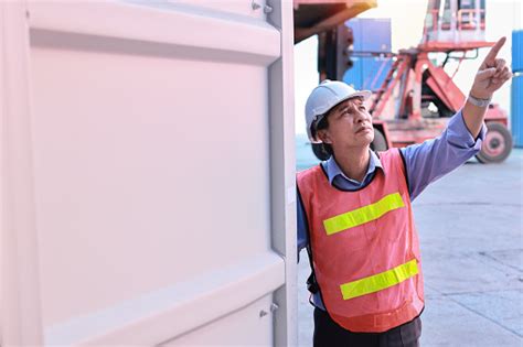 워키토키 무선 조종 적재 컨테이너 상자를 사용하는 감독 안전모를 쓴 엔지니어 또는 작업자는 컨테이너 화물 현장에서 산업용 컨테이너 화물 화물선을 가리키고 점검하는 작업을