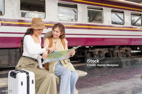 여행 개념입니다 여자 친구는 모자를 쓰고 가방과 짐을 들고 있습니다 기차역에서 기차를 기다리는 여성 여행자 2명에 대한 스톡