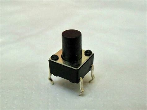 A Close Up Of A Black And White Push Button On A White Surface With Snow In The Background