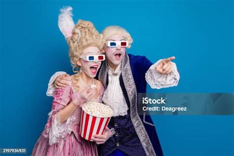 18세기 의상을 입은 커플이 생생한 파란색 배경에 3d 안경을 끼고 팝콘과 영화를 즐기고 있습니다 16 17 살에 대한 스톡 사진 및 기타 이미지 Istock
