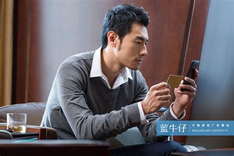 年轻商务男士拿着手机和一张名片 蓝牛仔影像 中国原创广告影像素材