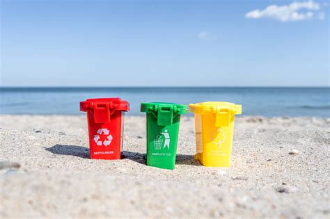 종이 플라스틱 유리 및 바다 전망과 모래 해변에서 재활용에 적합한 유기 폐기물이있는 다양한 색깔의 쓰레기통 쓰레기 분리 쓰레기