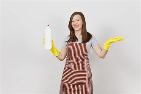 젊은 주부 노란색 장갑에 웃 고 줄무늬 앞치마 흰색 배경에 고립 매력적인 여자는 세척 및 청소 스폰지 대 한 청소기 액체 병을 들고 광고에 대 한 공간을 복사 가사 집안일에
