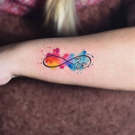 A Woman S Arm With An Infinite Sign Tattoo On It And Watercolor Stains