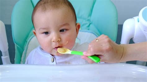 Mamá Alimenta Al Bebé Con Una Cuchara De Puré De Verduras En La Mesa De Alimentación De Los
