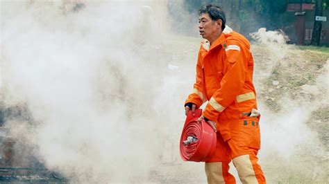 소방관은 화재 호스 화학 물 거품 스프레이 엔진을 사용하여 화염과 싸우고 소방관은 하드 모자 보호를위한 바디 안전 정장 유니폼을 착용합니다 소방 소화기 구조 훈련 건물