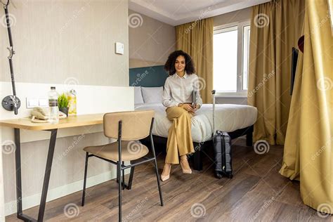 Pretty Young Business Woman Sitting On The Bed In The Hotel Room Stock