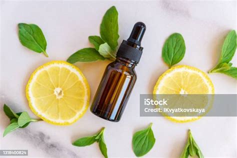 비타민 C 레몬 에센셜 오일을 곁들인 세럼 피펫이 달린 갈색 유리 병 대리석 배경에 민트 잎이 있는 레몬 조각 건강과 뷰티 컨셉 유기농 천연 화장품 감귤류 과일에 대한 스톡