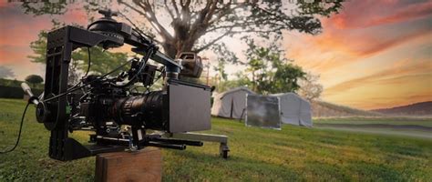 영화 카메라 야외 위치에서 영화 광고 또는 영화를 녹화하기 위한 비디오 카메라 뒤에 있습니다 비디오 제작을 위한 35mm 필름 스타일의 4k 디지털 카메라와 삼각대 돌리