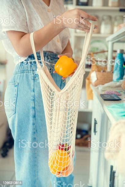 에코 숍에서 야채와 과일이 있는 끈 쇼핑백을 들고 있는 여성 친환경 스트링 재사용 가능한 넷 메쉬 백의 야채 폐기물이 없습니다 새로운 대체 구매 0에 대한 스톡 사진 및