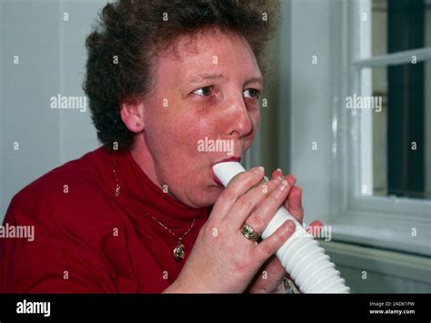 Lung Function Test Woman Breathing Into The Tube Of A Peak Flow Meter This Device Is Used To
