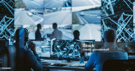 데스크톱 컴퓨터에서 작업하는 다민족 전문가가 있는 암실 대형 디지털 화면은 감시 위성 데이터 도시지도 및 Cctv 교통 영상 보고서를 보여줍니다 감시에 대한 스톡 사진 및