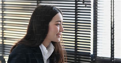 사무실에 앉아 웃고 컴퓨터 화면을 보고 있는 아름다운 젊은 여성의 초상화 사진 Unsplash의 태국 이미지