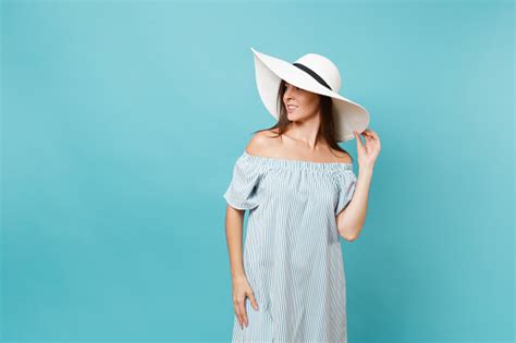 백색 여름 큰 넓은 가장자리 태양 모자 드레스에에서 아름 다운 젊은 여자 손 머리에 넣어 블루 파스텔 배경에 고립 된 복사