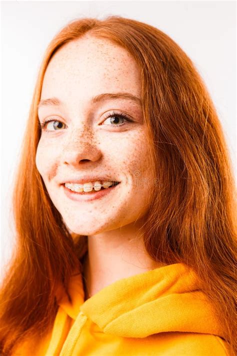 Портрет эмоциональной рыжеволосой девушки с веснушками и расчалками на белой предпосылке
