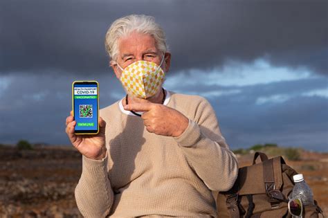 보호 얼굴 마스크를 착용 하는 노인 은 코로나 바이러스에 대 한 예방 접종 을 하는 사람들을 위한 건강 여권 애플 리 케이 션을