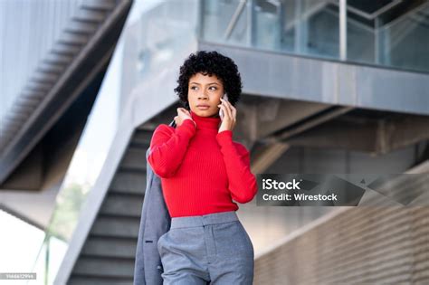 빨간 터틀넥과 양복을 입고 전화 통화를 하는 젊은 아프리카계 미국인 사업가 건축물에 대한 스톡 사진 및 기타 이미지 건축물 기업 비즈니스 단정한 사무복 Istock