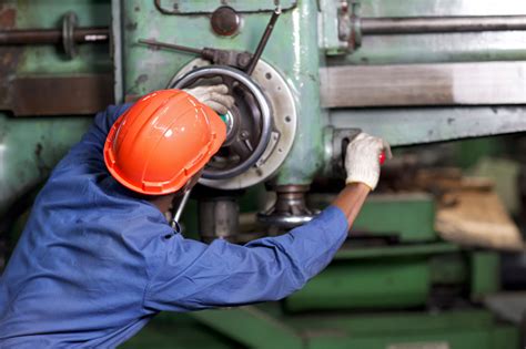 중공업 제조 공장에서 안전모로 작업을 제어하거나 산업 기계 프로세스를 확인하는 동안 보호 유니폼을 입고 컴퓨터를 사용하는 후면 기술자 엔지니어 20 24세에 대한 스톡 사진