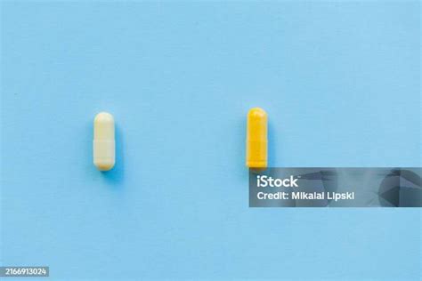 평범한 파란색 배경에 노란색과 흰색이 다른 두 개의 정제 약물 또는 의료 중독 옳고 그른 알약 선택 0명에 대한 스톡 사진 및