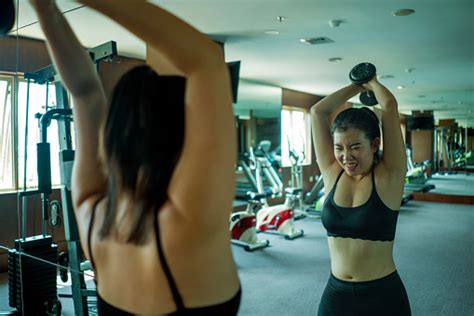 거울 초상화 의 젊은 예쁜 과 맞는 아시아 여자 열심히 일하는 호텔 체육관 또는 피트니스 센터 리프팅 아령 몸 건물 실내 운동에서 건강한 라이프 스타일 개념 건강한 생활