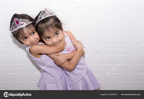 Female Asian Identical Twins Sitting On Chair With White Backgro Stock Photo By Bill Roque