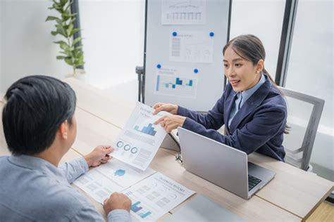 현대 사무실에서 새로운 프로젝트에 대해 논의하면서 랩톱 컴퓨터와 그래프 문서를 사용하여 함께 일하는 아시아인 동료들 2명에 대한 스톡 사진 및 기타 이미지 Istock