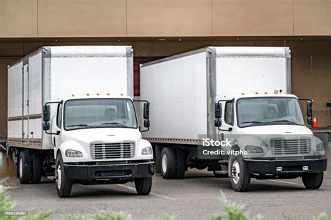 박스 트레일러가 있는 두 대의 중간 택시 세미 트럭이 다음 현지 배송을 위해 화물을 적재하는 창고 부두에 서 있습니다 배달에 대한 스톡 사진 및 기타 이미지 Istock