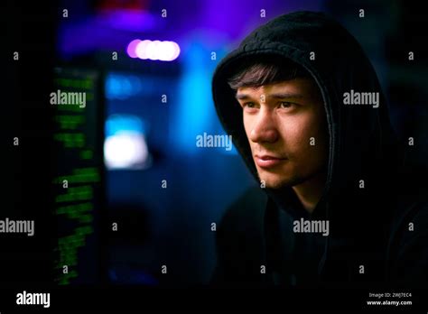 Low Key Lighting Shot Of Male Computer Hacker Sitting In Front Of Screens Breaching Cyber