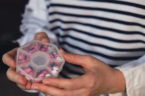 여자 분류 알약 주최자 주간 샷 매일 흰색 분홍색 약물과 캡슐로 약을 복용하기위한 정제의 복용량과 의료 알약 상자의 근접 촬영 집에서 매일 비타민을 섭취하는 젊은 여성 건강