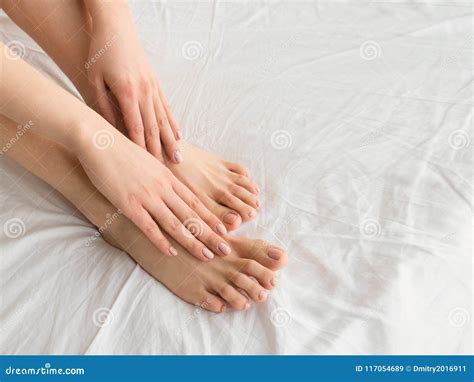 Woman Holding Her Tired Feet In Hand Sitting On Bed With White Sheets Stock Image Image Of
