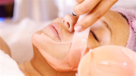 미용사는 여성 얼굴에 스크럽을 적용합니다 얼굴 관리를위한 미용 절차에 스파 살롱에있는 여성 40 44세에 대한 스톡 사진 및