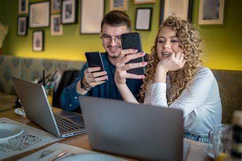 카페에서 커피 데이트를 하는 커플 스마트폰을 함께 사용하면서 커피를 마시고 수다를 떨기 2명에 대한 스톡 사진 및 기타 이미지