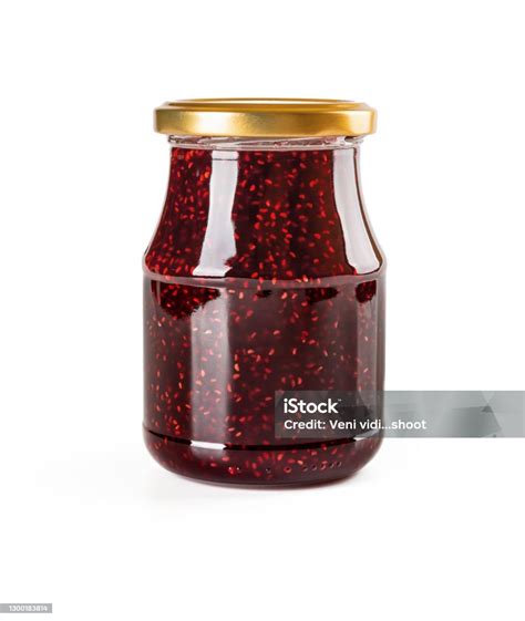 흰색 배경에 고립 된 황금 뚜껑이있는 유리 항아리에 맛있는 달콤한 라즈베리 잼 전통적인 수제 레드 베리 젤리 마멀레이드 또는