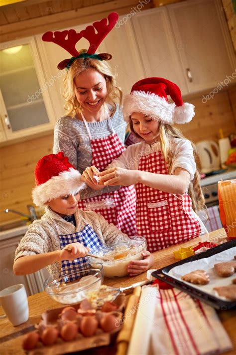 niños sonrientes y madre horneando galletas de Navidad en casa
