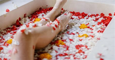 열대 꽃이 있는 욕조에 누워 욕실에서 휴식을 취하고 호텔에서 스파 절차와 아침 일과를 즐기는 젊은 성인 여성의 수직 및 자른 보기 사진 Unsplash의 발 이미지