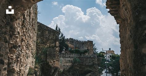 언덕 위의 성으로 이어지는 돌 아치형 통로 사진 Unsplash의 무료 도시의 이미지