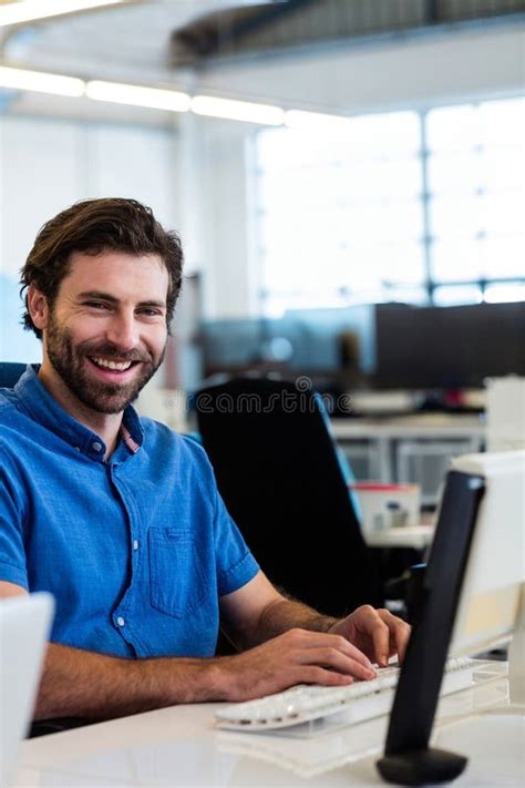 Man Typing On White Keyboard At Desk In Open Plan Office With Desktop