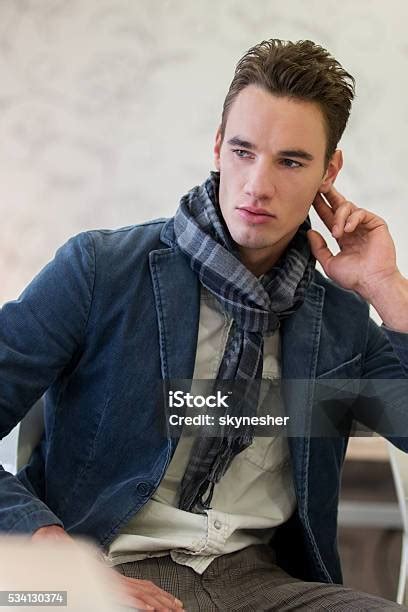 젊은 카메라를 향해 미소 짓는 생각에 잠긴 남자 휴식 실내 및 루킹 한통입니다 고독 개념에 대한 스톡 사진 및 기타 이미지 고독 개념 고독 부정적인 감정 표현 남성