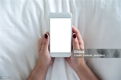 하얀 침대에 앉아 텅 빈 데스크탑 스크린으로 흰색 휴대 전화를 들고 여자의 손의 상단 보기 이랑 이미지 형판에 대한 스톡 사진 및 기타 이미지 Istock