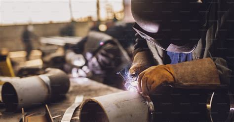 보호 유니폼을 입은 용접기와 불꽃이 튀는 동안 산업 테이블에 금속 파이프를 용접하는 마스크 사진 Unsplash의 작업장 이미지