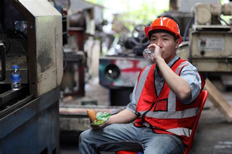 보호복을 입은 아시아의 기술자 엔지니어 또는 노동자가 산업 제조 공장에서 점심을 먹고 샌드위치와 물을 먹는다 30 34세에 대한 스톡 사진 및 기타 이미지 Istock