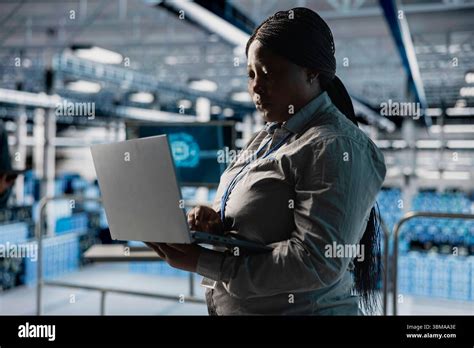 Data Center Female System Administrator Using Laptop Configuring